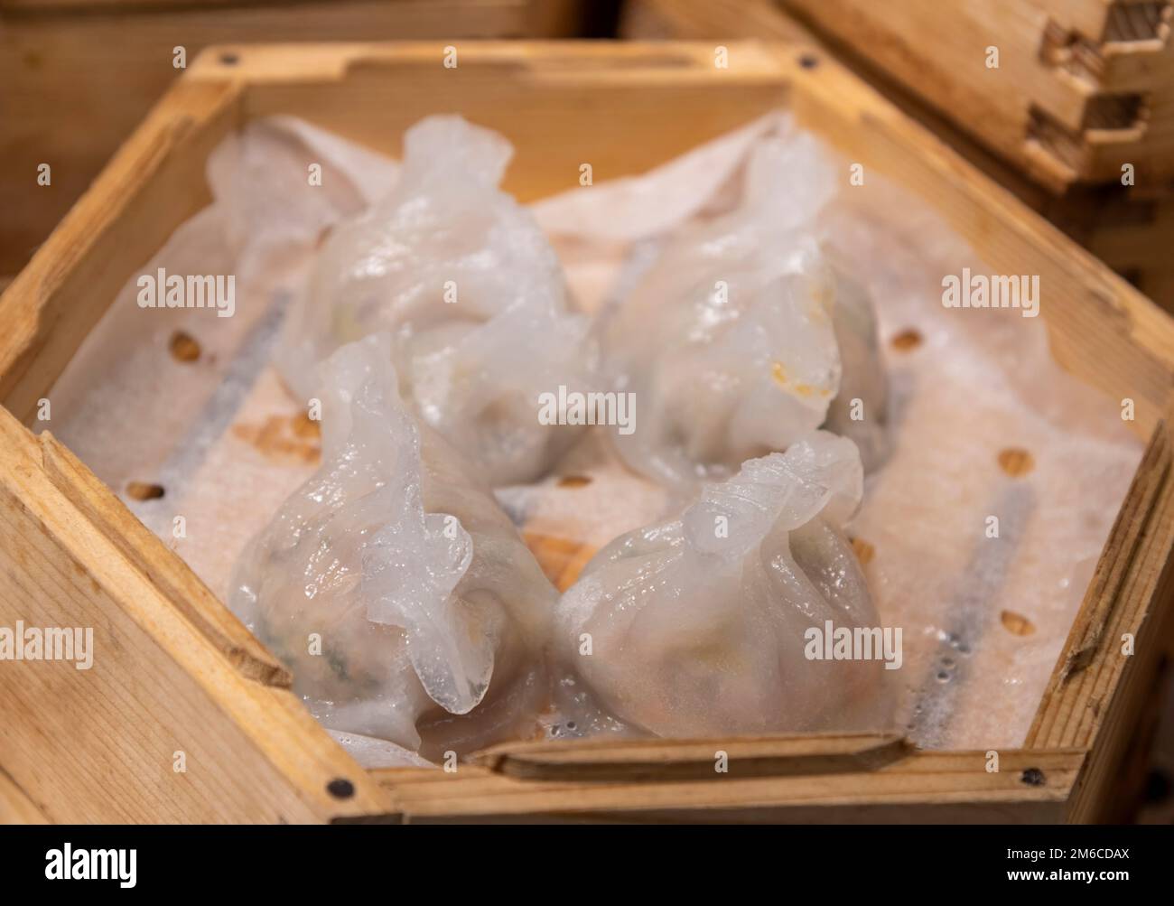 A closeup shot of steamed dumplings in Chinese bamboo tray with blur ...