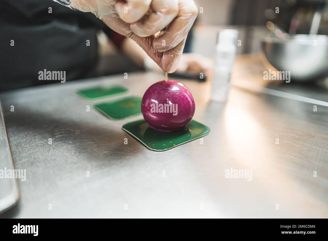 Round cake decorated with pink icing being placed on a green square ...