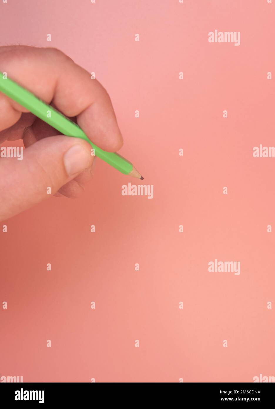The man writes with his left hand. Pink background. Place for text ...