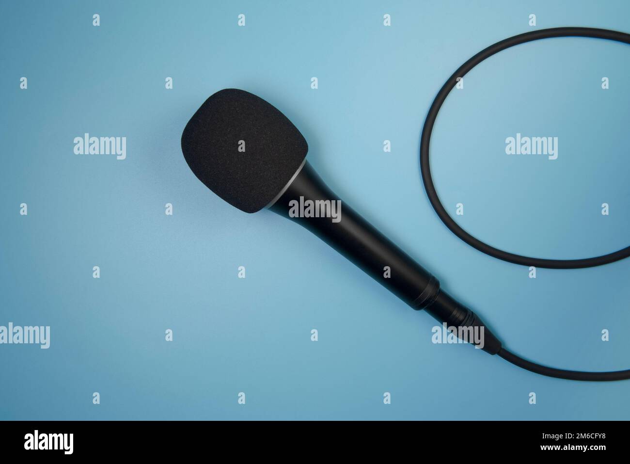 Concert microphone connected by cable on a blue background. Close up ...