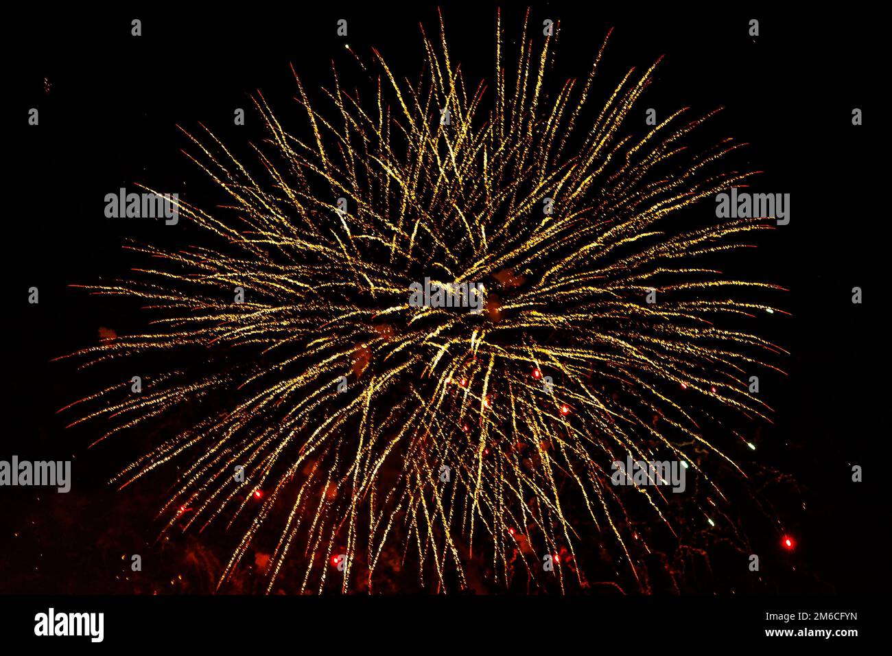 In the night sky, a volley of fireworks in the form of curved yellow ...