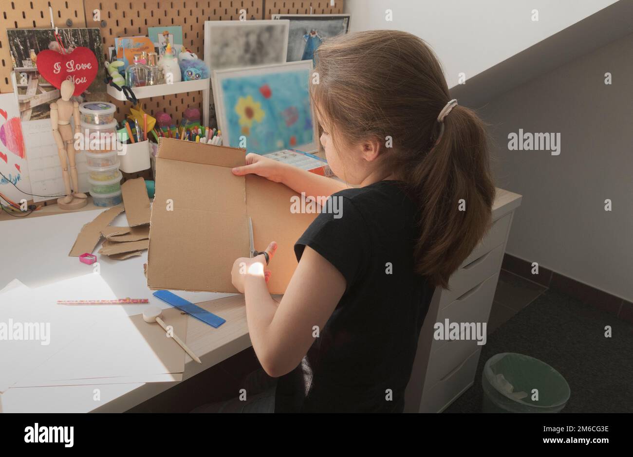 Girl making crafts with scissors and carton at home Stock Photo - Alamy