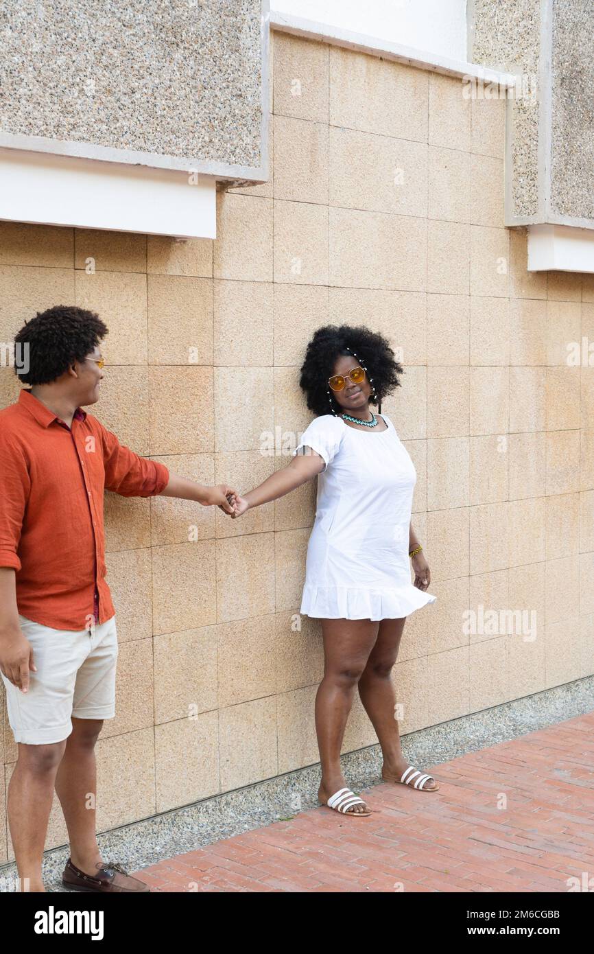 friends standing against a wall, talking, laughing and enjoying each ...