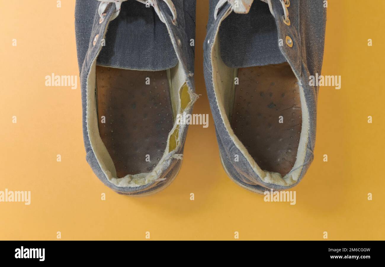 Old worn torn sneakers. On mustard background. Back side Stock Photo ...