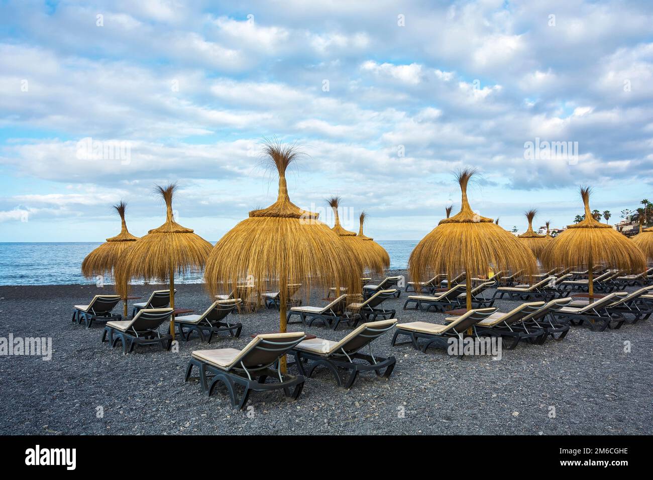 Empty sun beds and straw umbrellas on a beach of pebbles Stock Photo ...