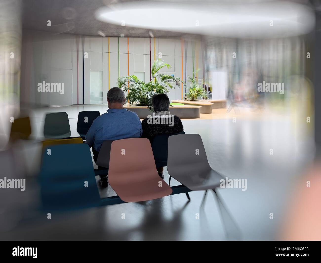 Rear view of couple waiting inside modern large new hospital room hall ...