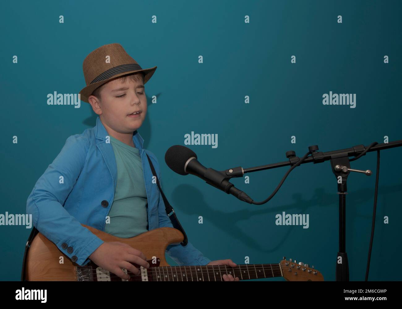 The boy is sings and rehearsing the electric guitar. On a blue ...