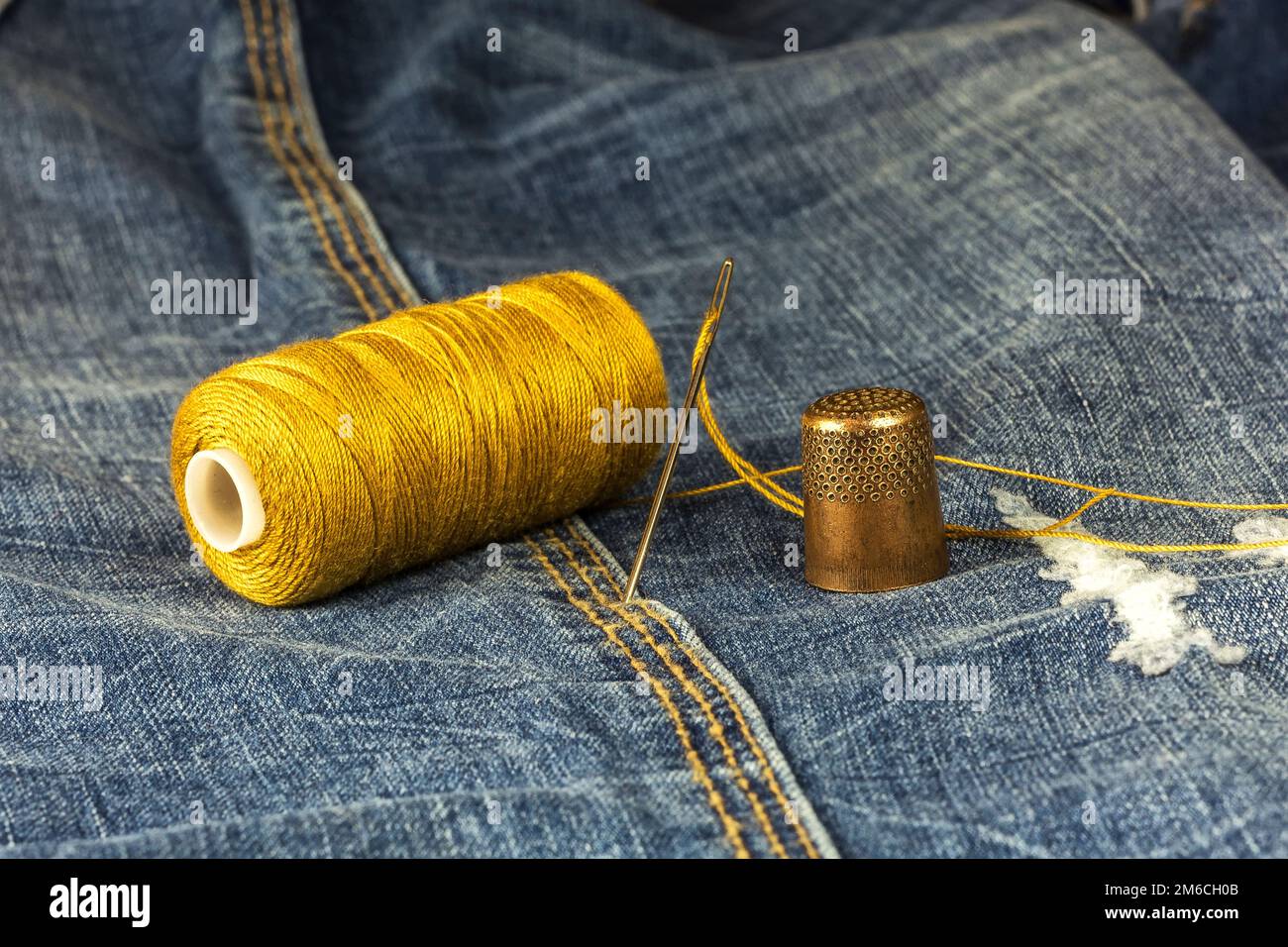 Denim fabric with needle, thread and thimble Stock Photo - Alamy