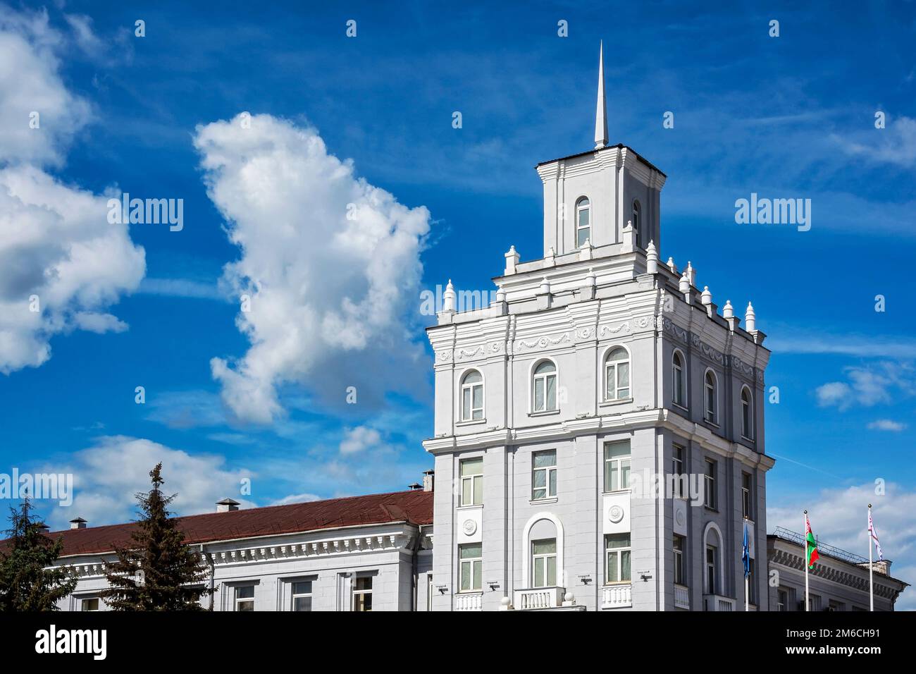 High square building with a spire on the roof on blue sky background ...