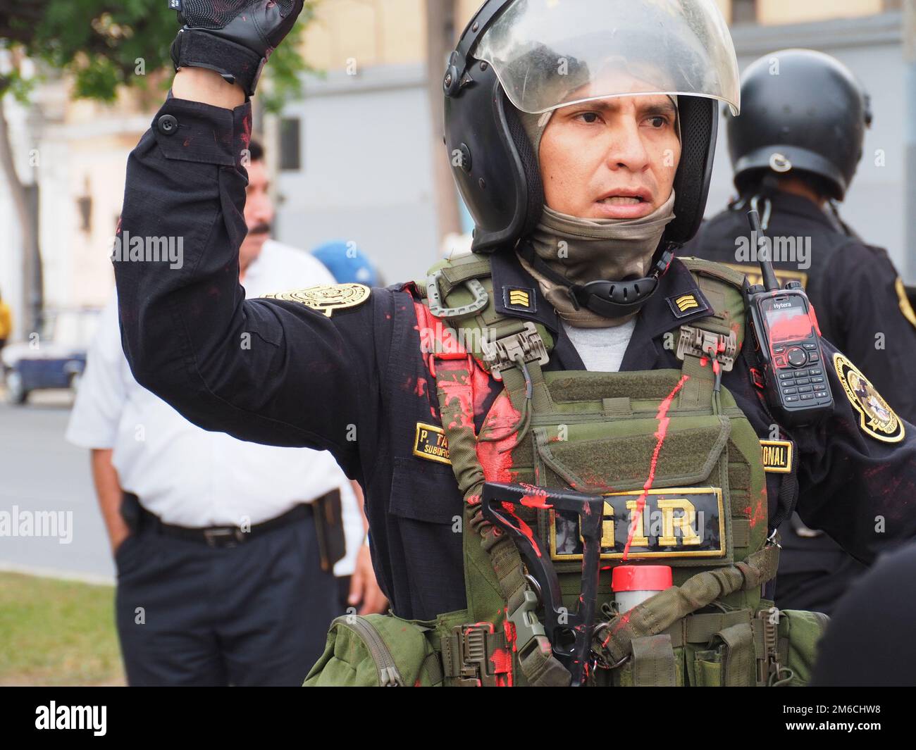 Policeman stained with red paint when hundreds march for peace in Lima ...