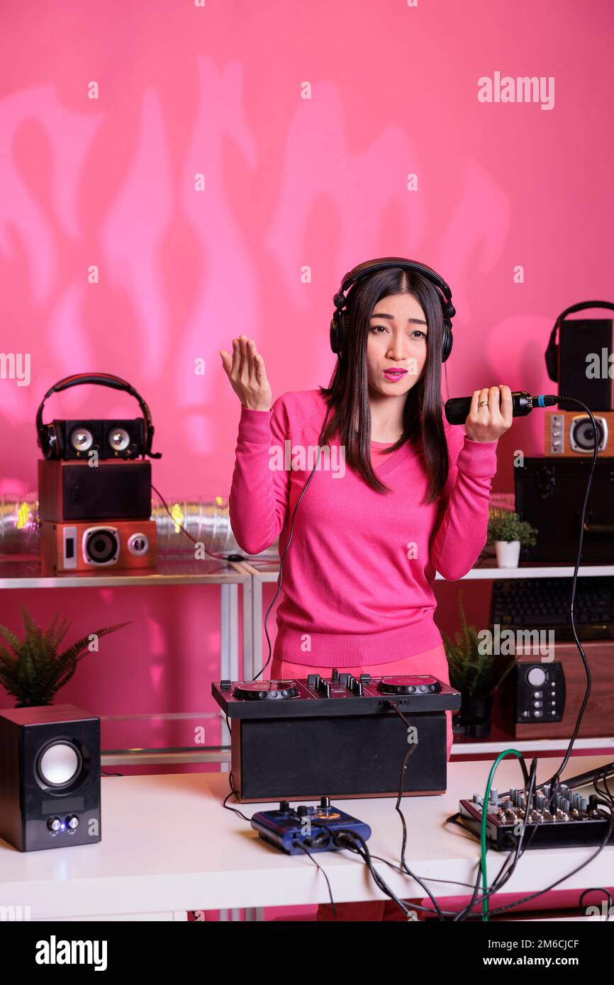 Asian musician standing at dj table mixing electronic sounds with ...