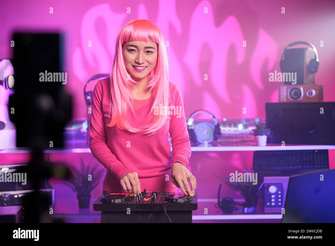 Asian dj performing techno song using mixer console while recording ...