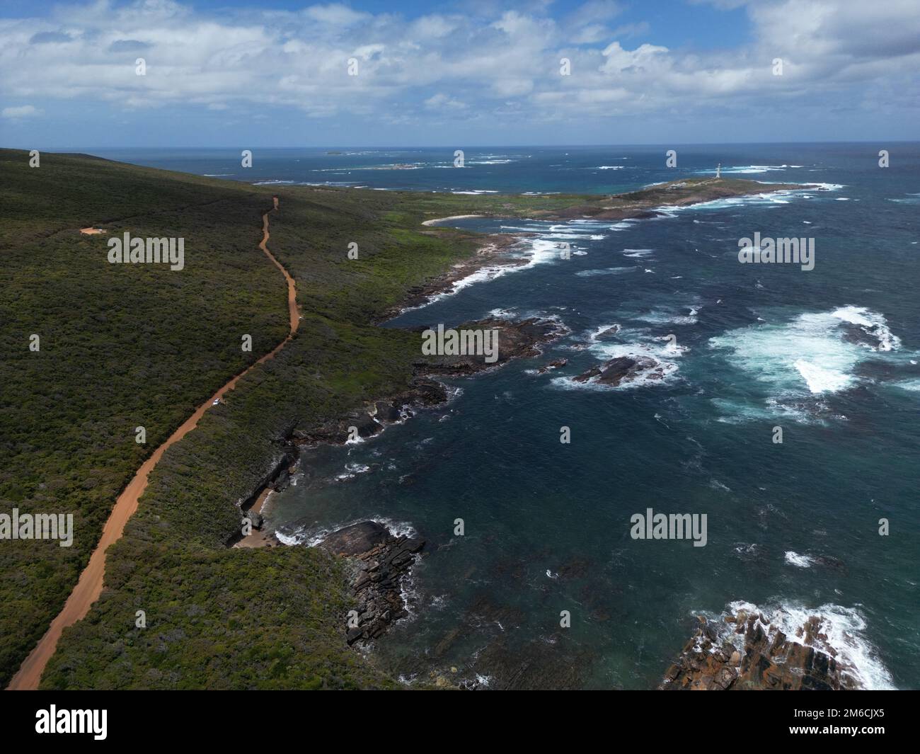 A narrow pathway on cliff covered with nature near the sea under blue ...