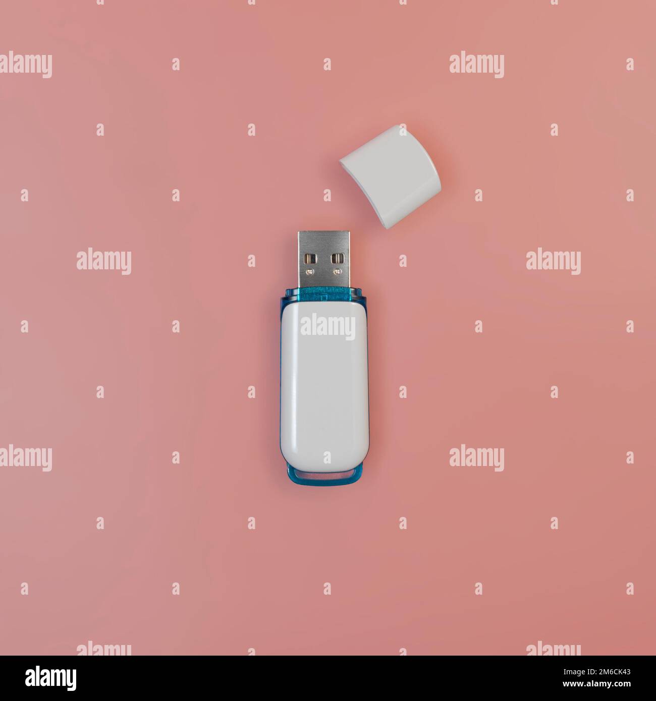 White usb flash stick with lid. On a pink background. Close-up, top ...
