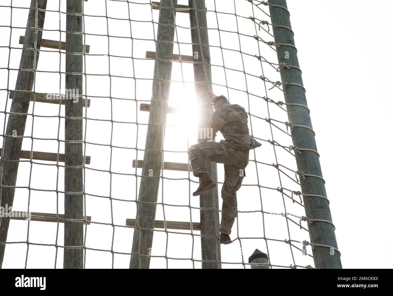 A service member climbs down the rope web during the obstacle course ...