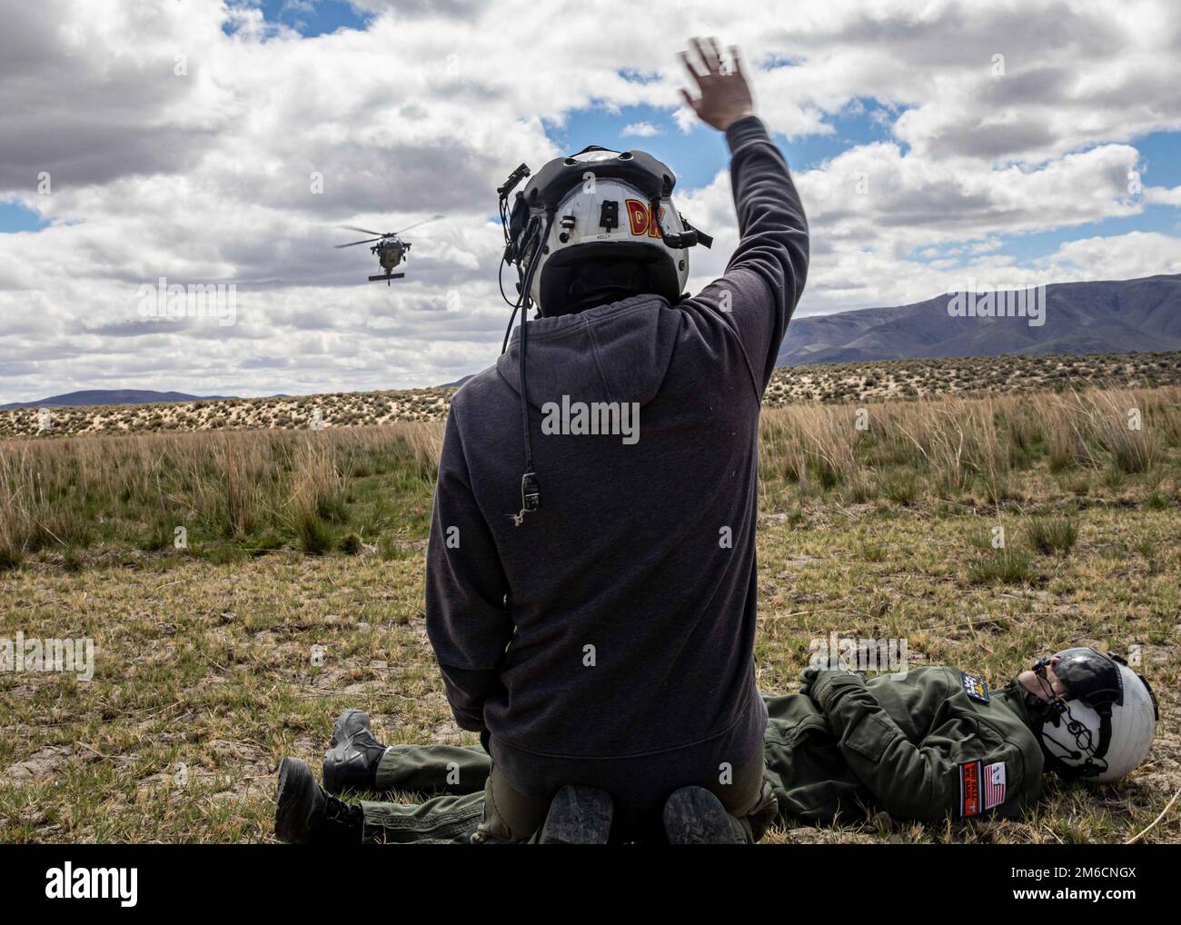 Lt. Dylan Kelly, center, signal to an MH-60S Knighthawk helicopter as ...