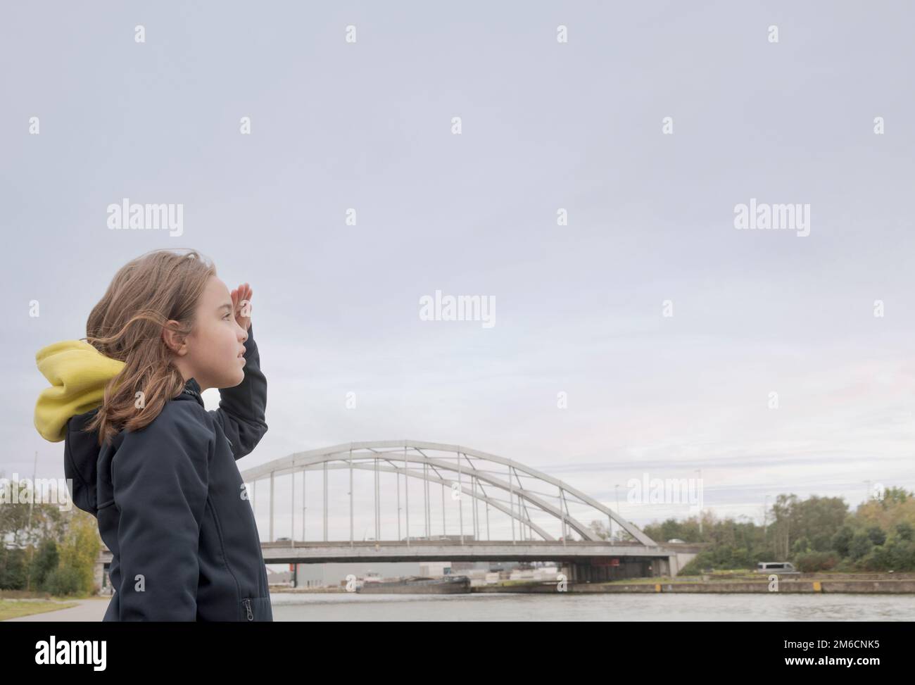 Teenage girl looking into the distance against a gray autumn sky and a ...
