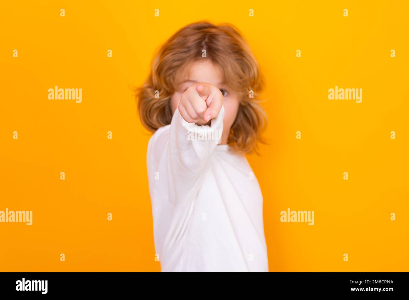 Surprised child pointing at you on yellow isolated studio background ...