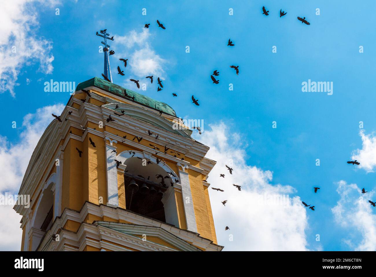 Tower of the Christian temple with bells and a cross into which flies a ...