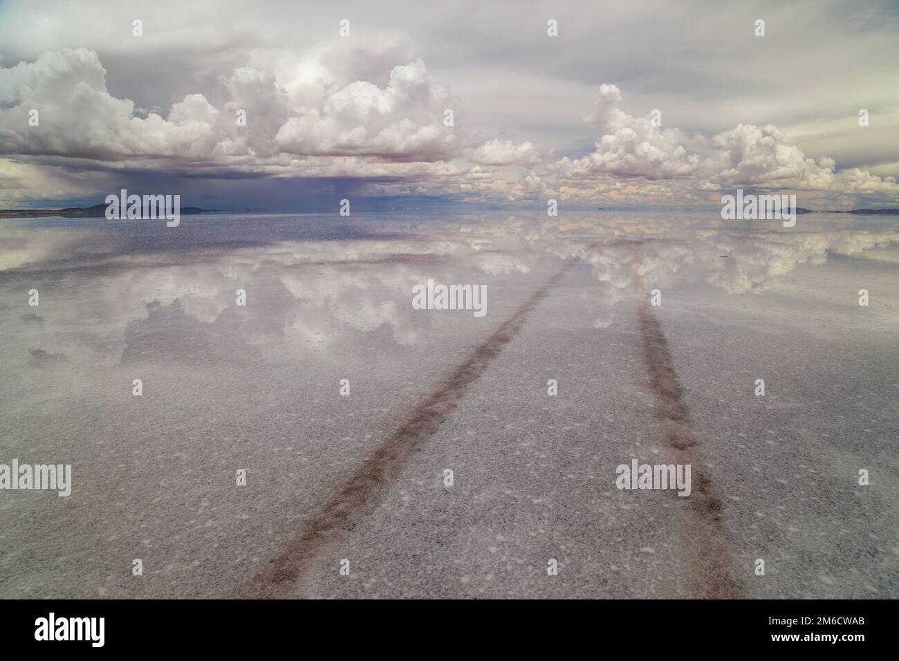Flooded salt flats with reflection of clouds in the water and a car ...
