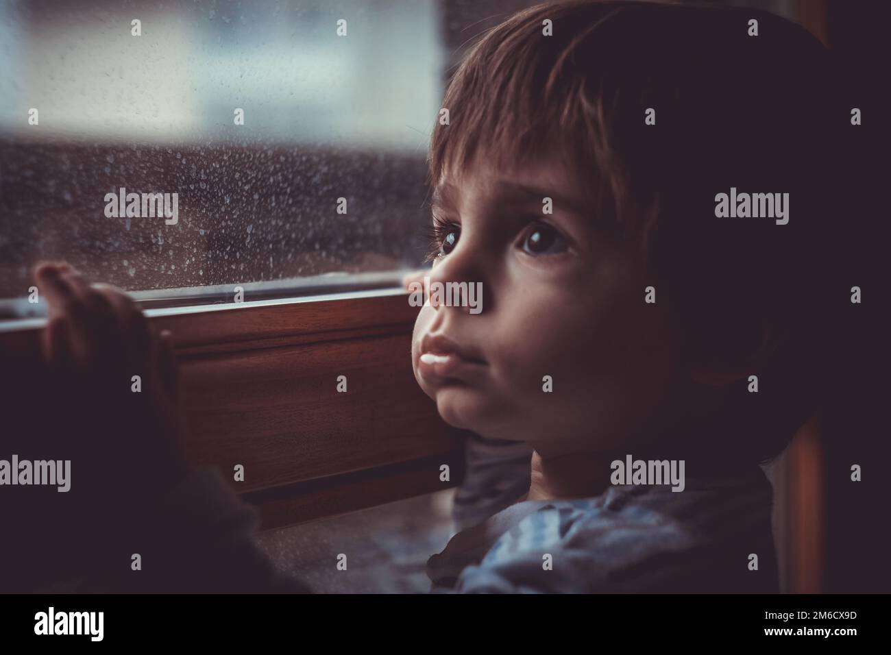 Little boy looking through the windows to the cloudy sky in Muti Stock ...
