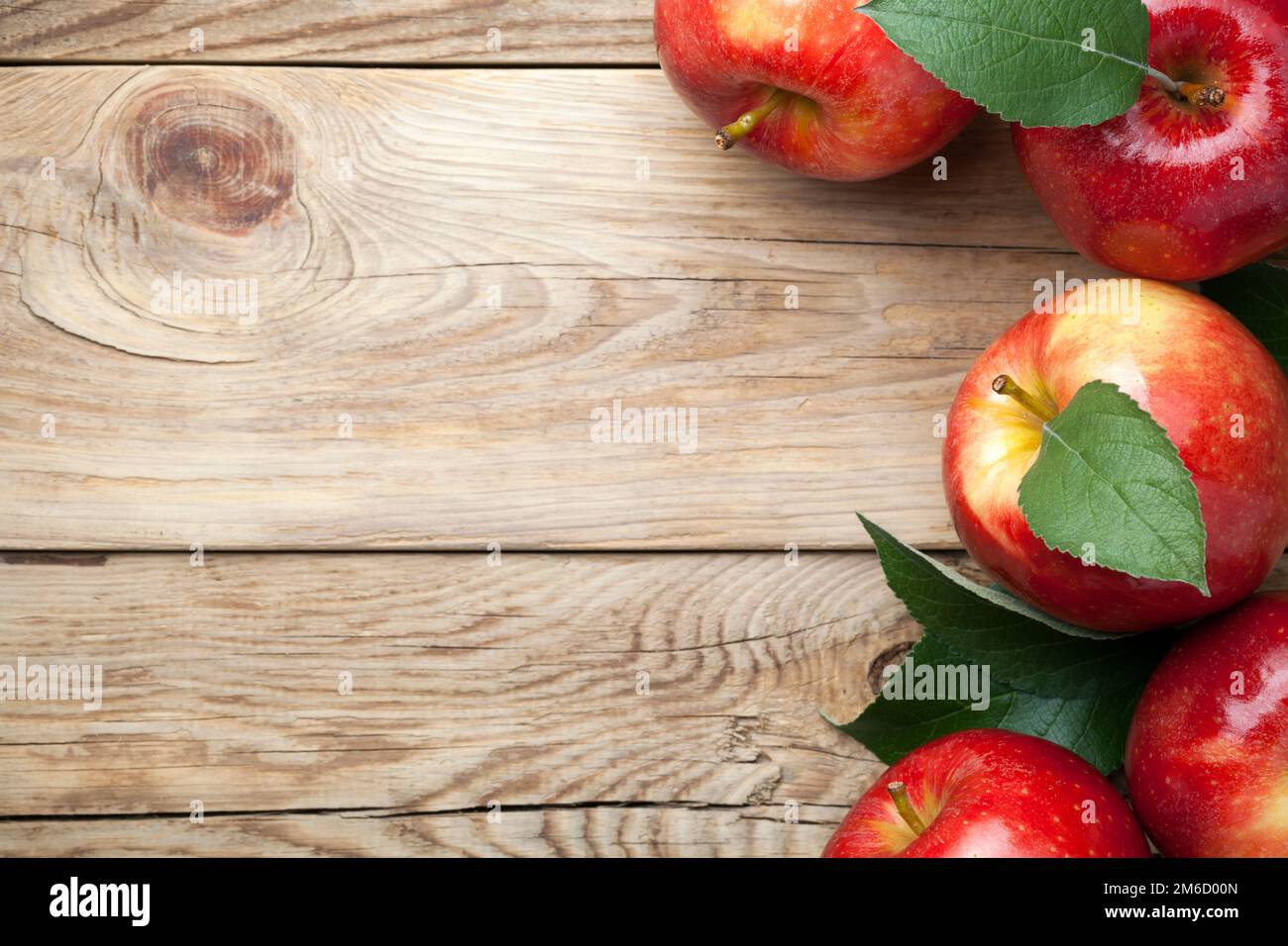 Red Apples with Green Leaves on Wooden Table Stock Photo - Alamy