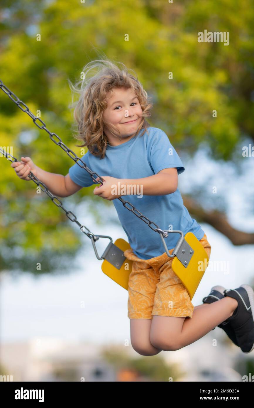 Child boy on swing. Kid swinging on playground. Cute excited amazed child on swing. Cute child ...