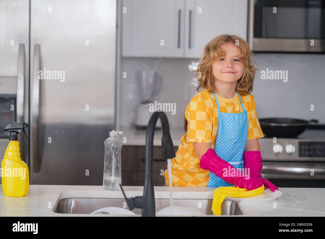 Cleaning at home. Child washing and wiping dishes in kitchen. American ...