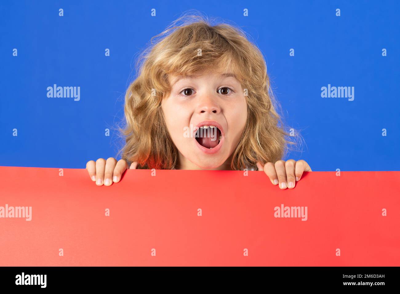 Excited kid boy hold red blank banner on studio background. Advertising ...