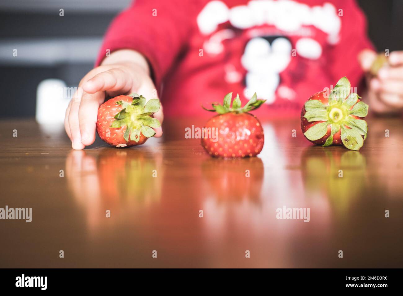 Child grabbing a strawberry from a fruit line on the table Stock Photo ...