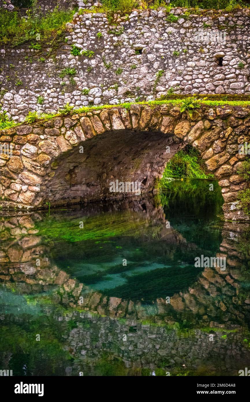 Round stone bridge reflected in river water vertical background Stock ...