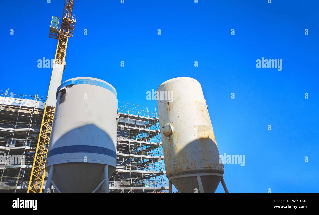 Mortar silos at construction site with crane and blue sky Stock Photo ...