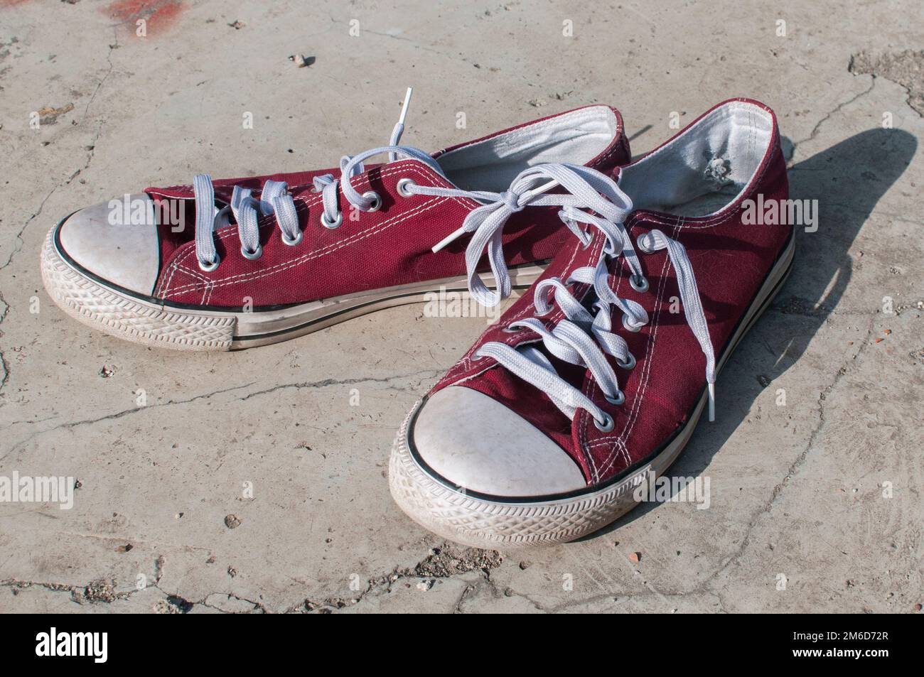 Pair of worn out vintage red old canvas sneakers on outside concrete ...