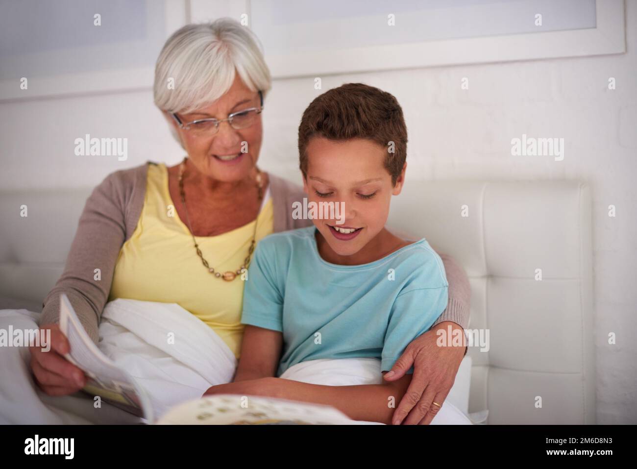 Story time with gran. A grandmother reading a book to her grandson in ...