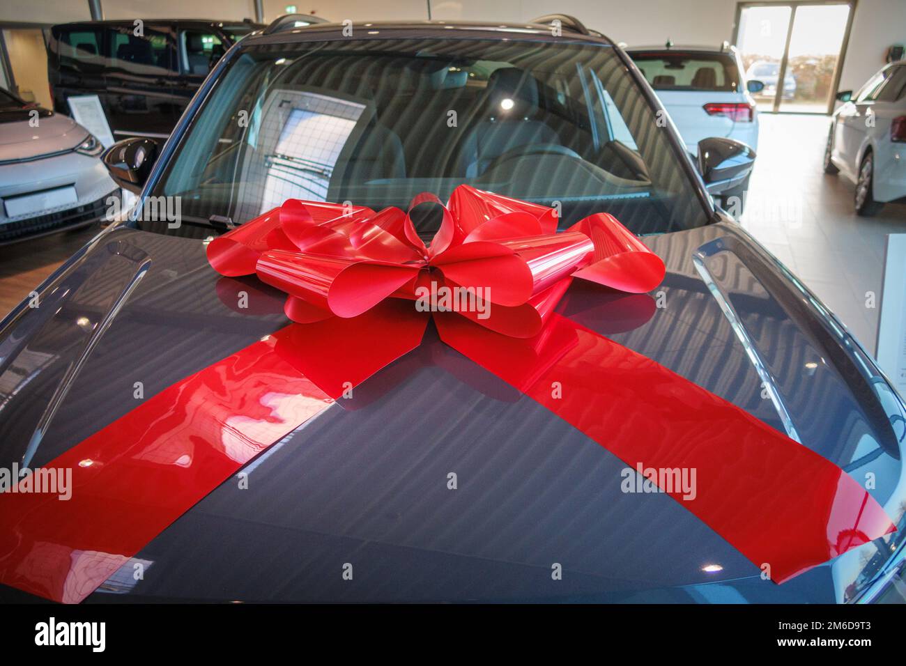 a big red ribbon is on the hood of a new car Stock Photo - Alamy