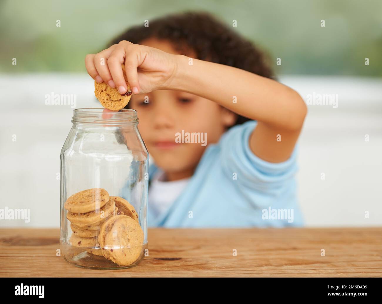Mmm, so many cookies just for me. A cute young boy grabbing a cookie ...