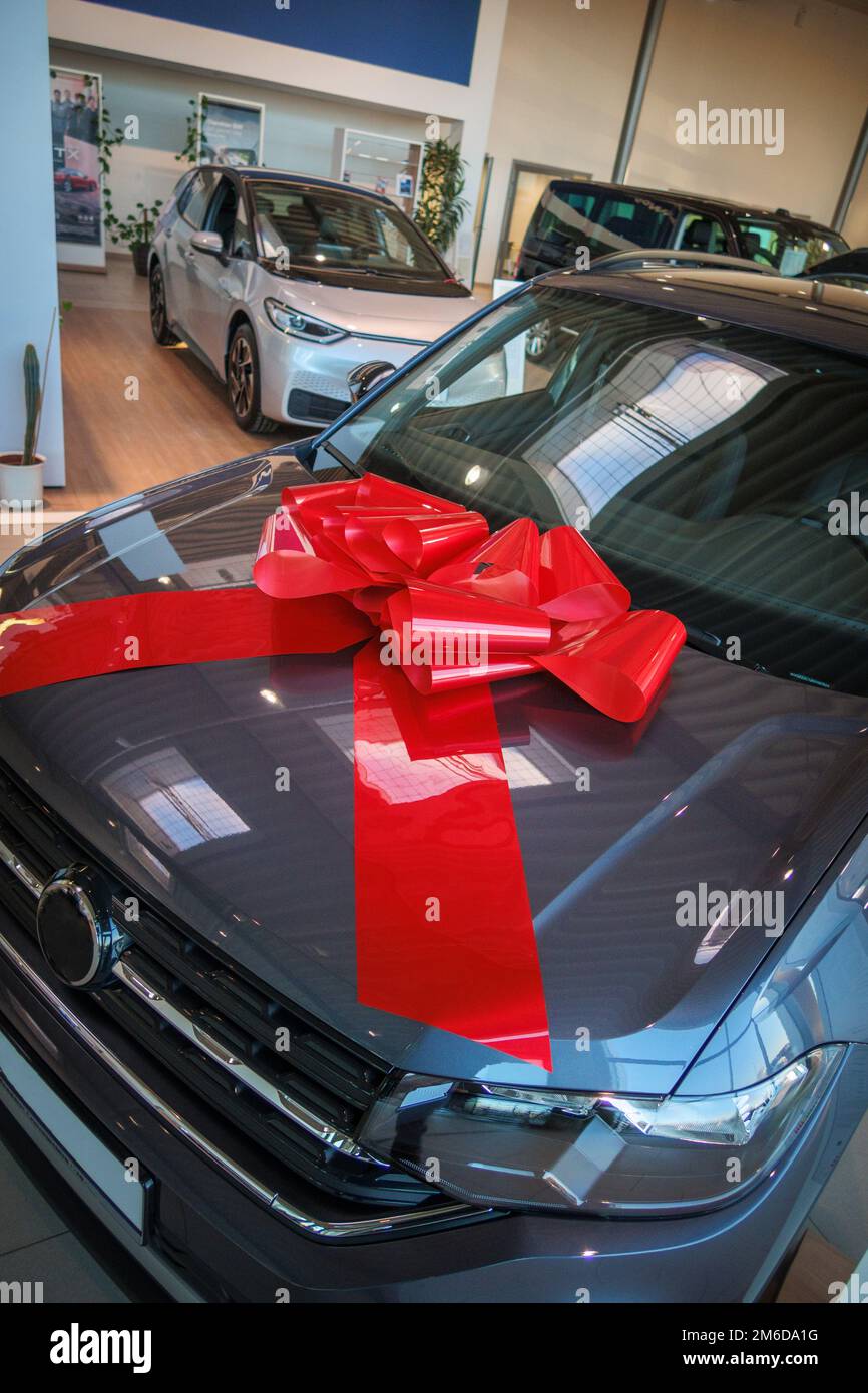a big red ribbon is on the hood of a new car Stock Photo - Alamy