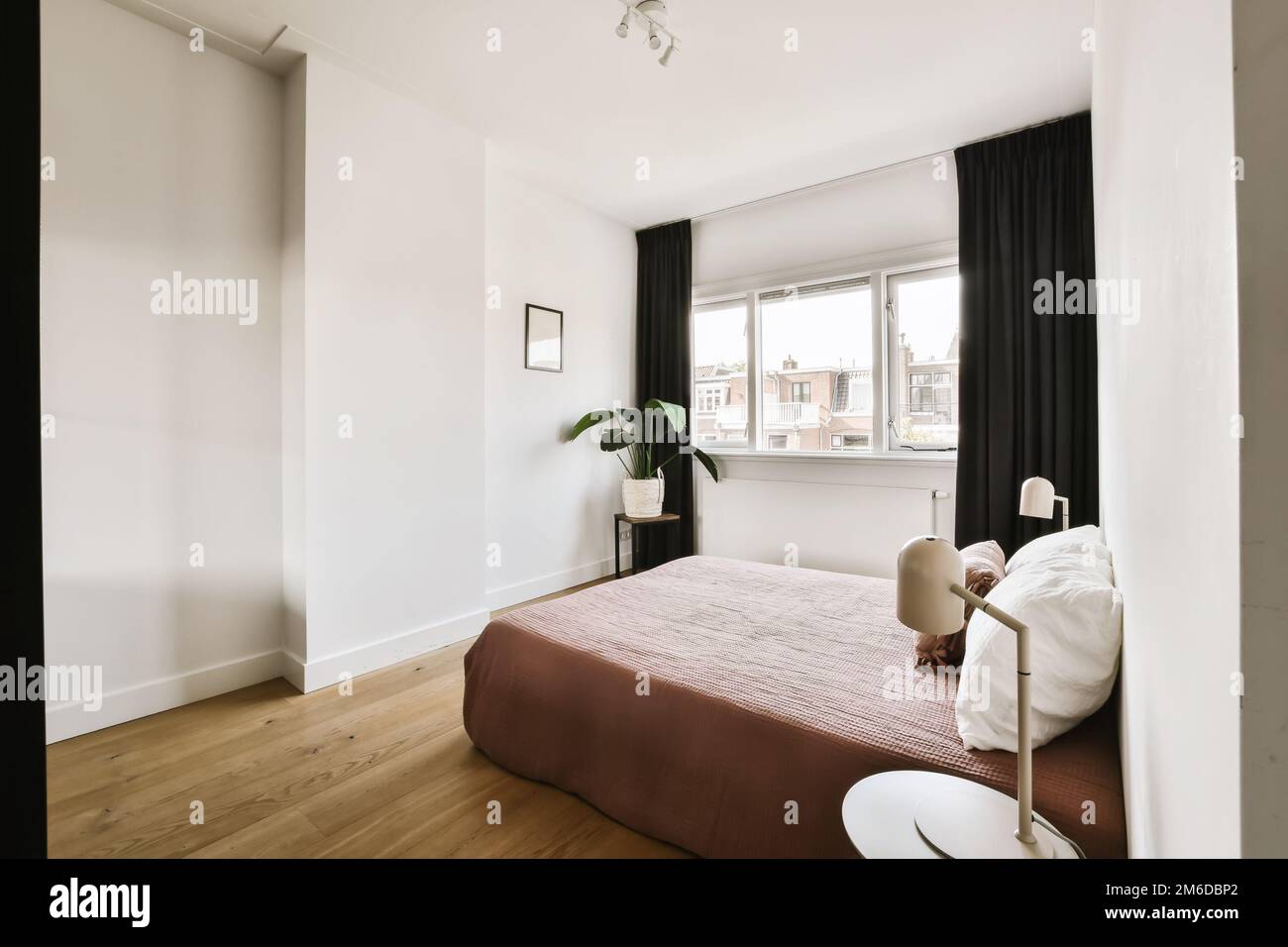 a bedroom with white walls and wood flooring the room is well lit by ...