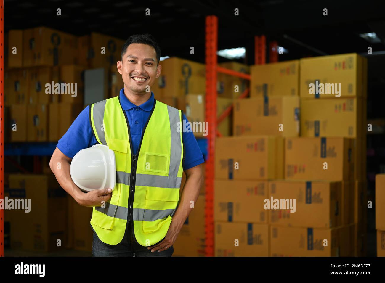 Industrial manager in yellow vest and holding hard hat in hand standing ...