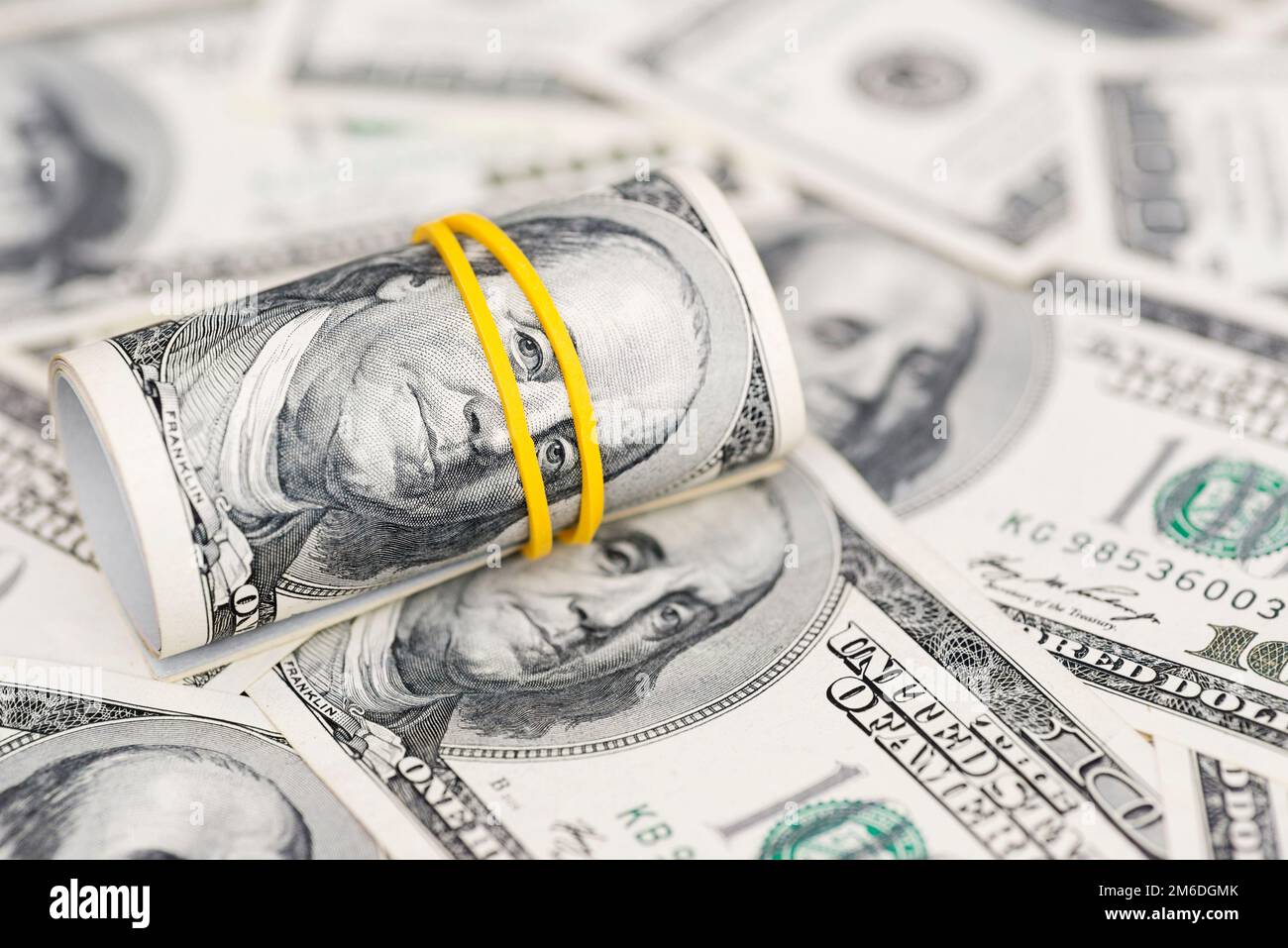 A roll of 100 dollar bills closeup on pile of American dollars ...