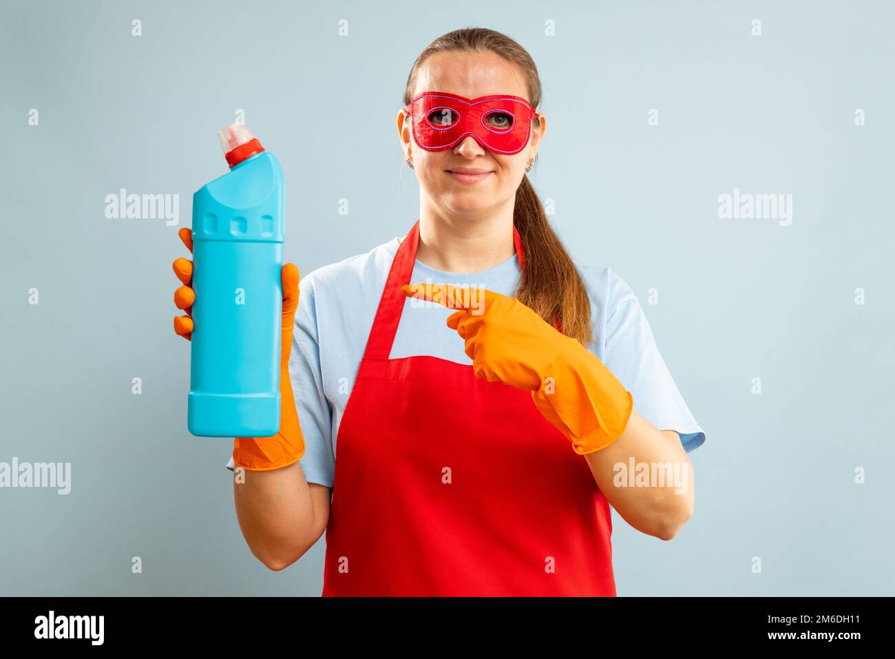 Woman in red mask, rubber gloves and apron holding cleaning agent ...