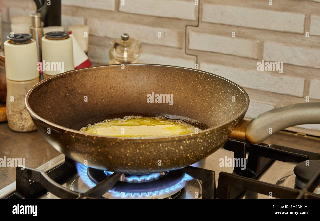 Butter is melted in frying pan on gas stove Stock Photo - Alamy