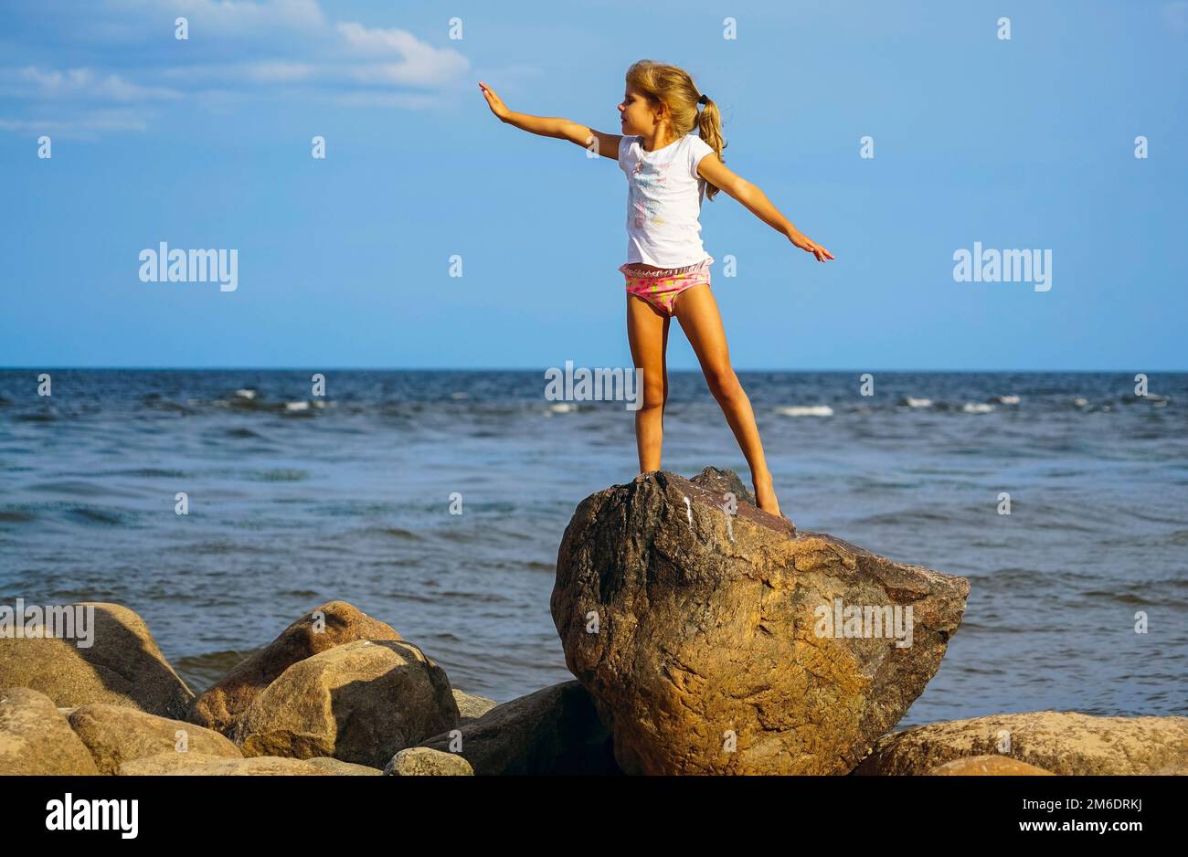 A girl on the shore of the lake is standing in a beautiful pose on the ...