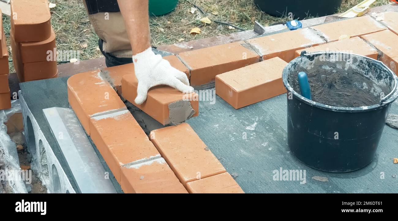 A man builds a brick wall. Brick put on the solution. Construction of ...