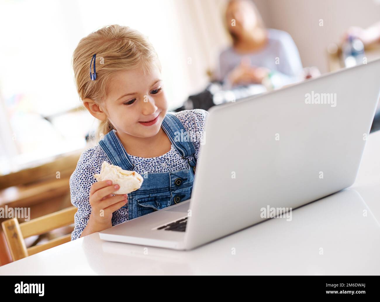 Multi-tasking like a little champion. a cute little girl using a laptop ...