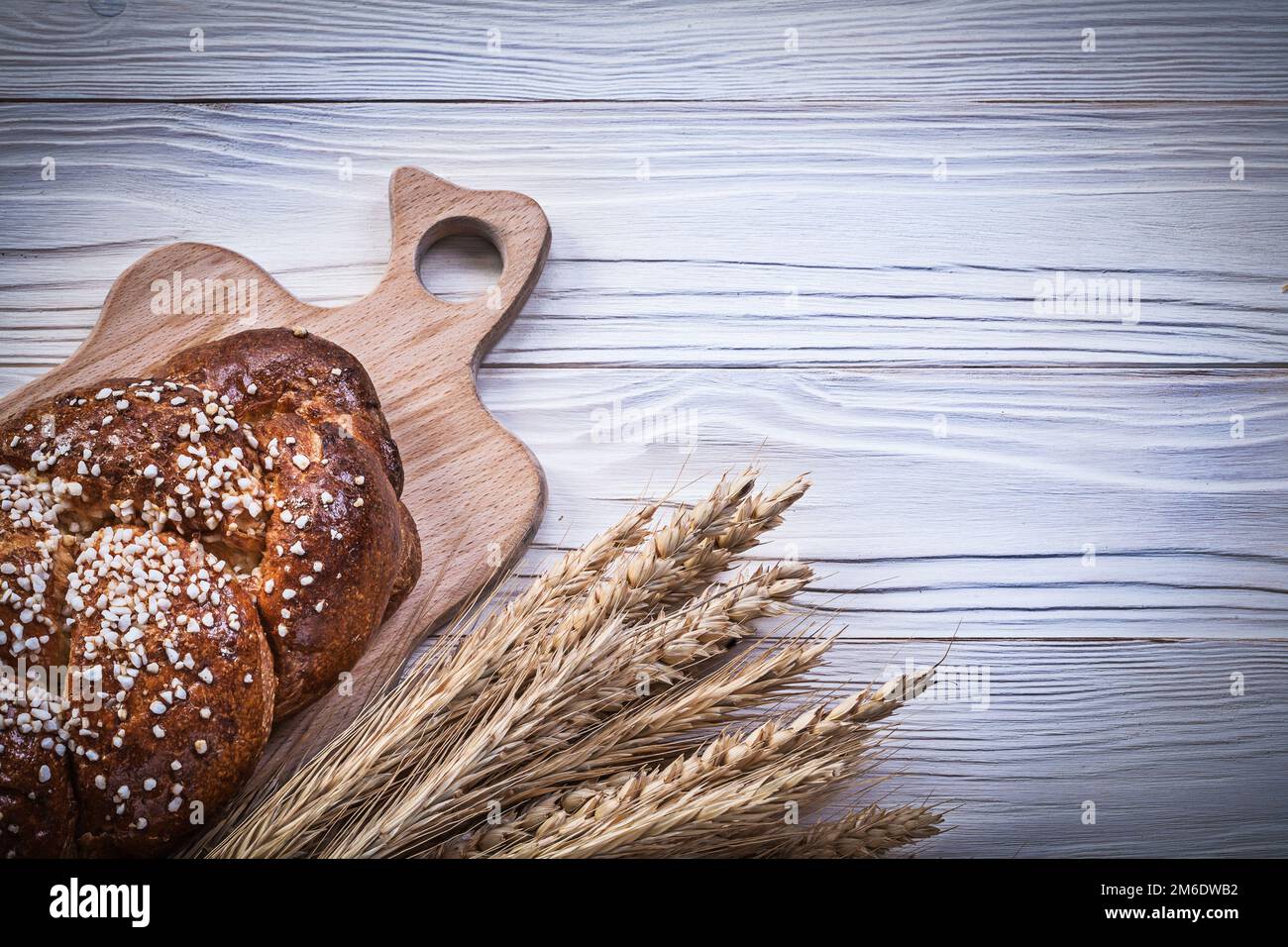 Chopping board bunch of wheat rye ears bread stick on wooden background ...