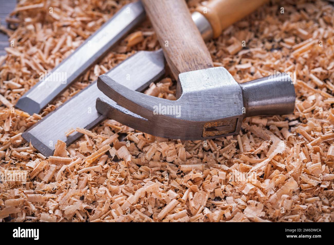 Claw hammer and chisels in wooden shavings on vintage wood board ...