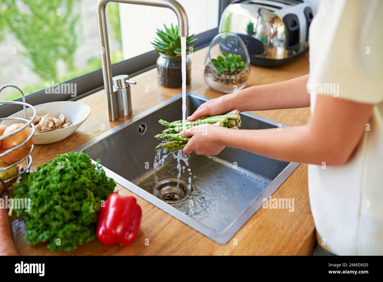 Always clean your veggies. a woman washing vegetables in a kitchen sink ...