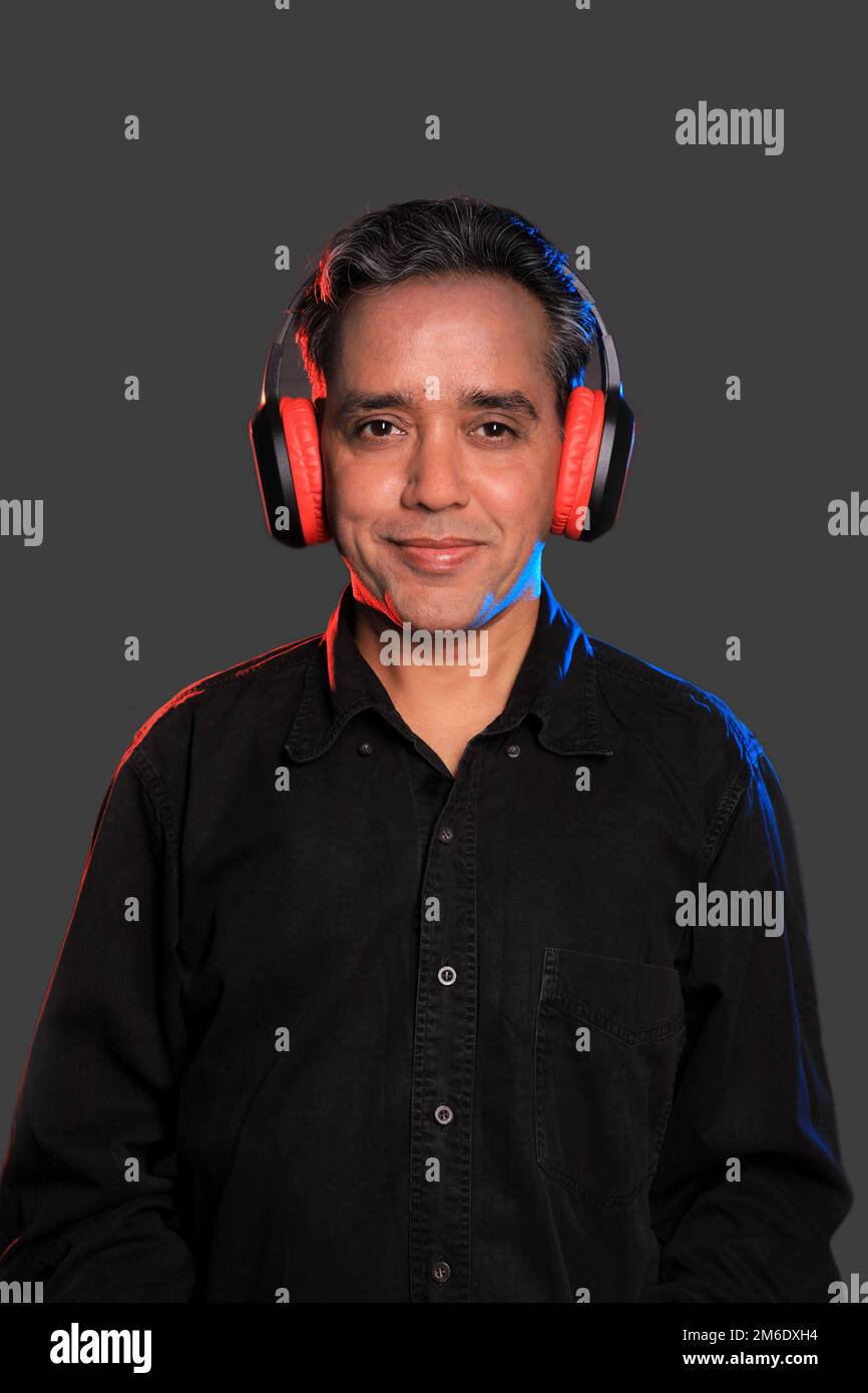 Indian man with wireless headphones on grey background Stock Photo - Alamy