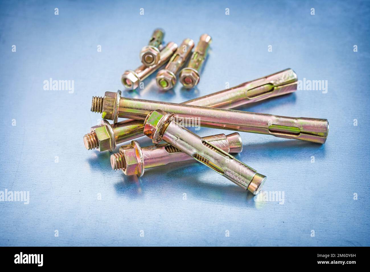 Set of metal anchor bolts with construction nuts on metallic background ...